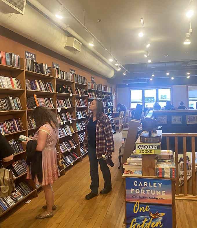 Village Books and Paper Dreams shoppers browse the fiction section while others relax in the background caf&eacute; area.
