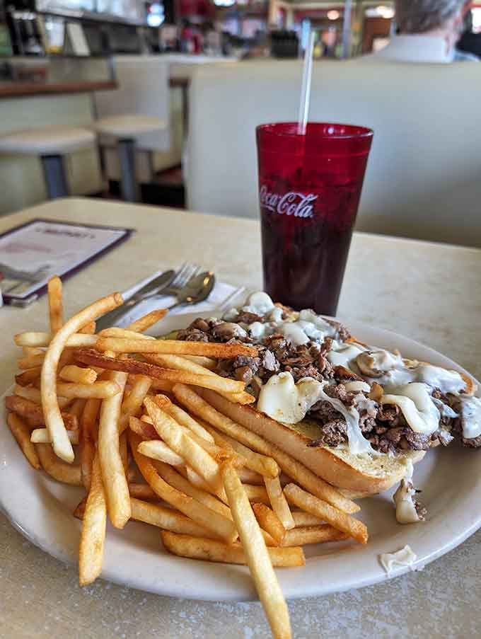 The cheesesteak loaded with beef and cheese alongside a mountain of fries is pure indulgence in edible form.