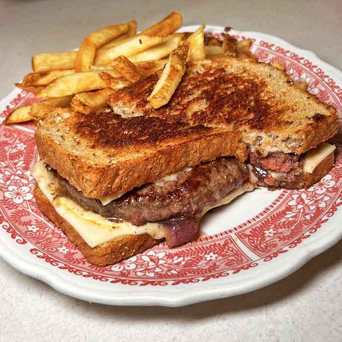 The patty melt arrives on griddled bread with fries, proving that some sandwiches deserve architectural awards.