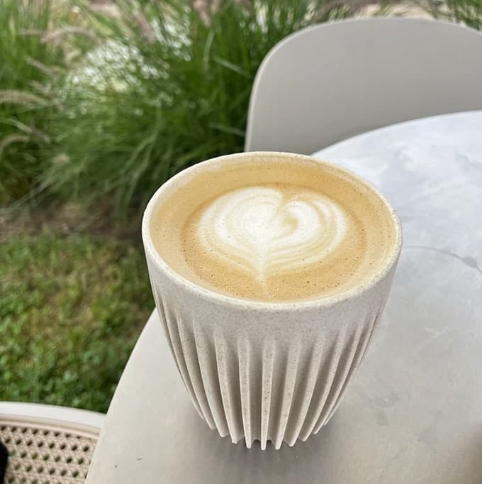 Latte art in a sculptural cup that's almost too pretty to drink, like someone combined coffee with modern art appreciation.