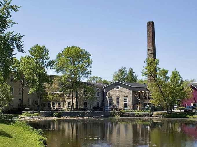 The old mill's smokestack stands tall beside still waters, a reminder of Cedarburg's industrious past now transformed into artistic present.