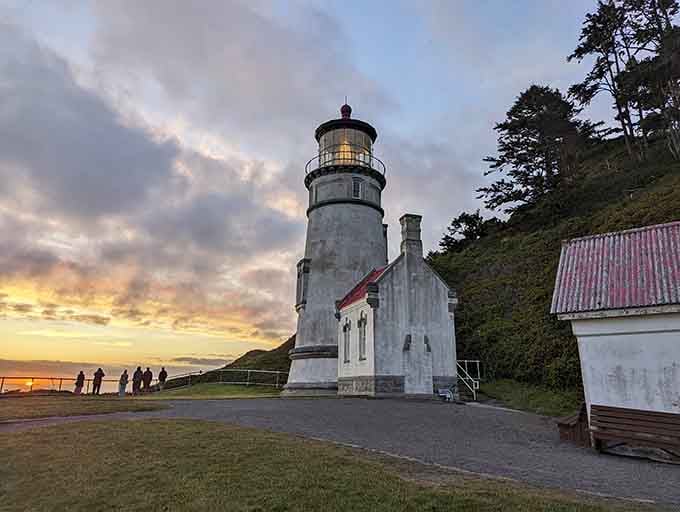 Sunset gilds the lighthouse tower as visitors gather to witness nature's nightly show from this dramatic coastal perch.