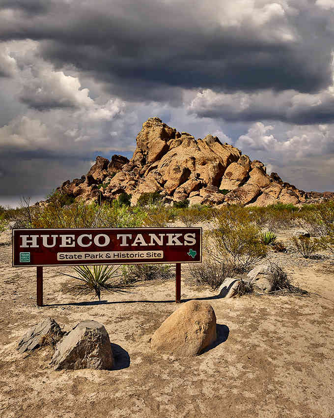 Dramatic storm clouds gather above ancient rock formations, creating a Wild West landscape that photographers dream about.