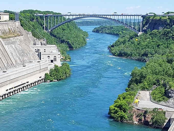 The Niagara River flows brilliant turquoise beneath that bridge, powerful enough to remind you nature always has the final word.