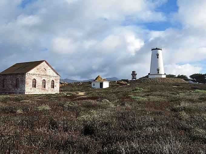 The historic stone building beside this white tower adds an Old World European charm to the windswept coastal landscape.