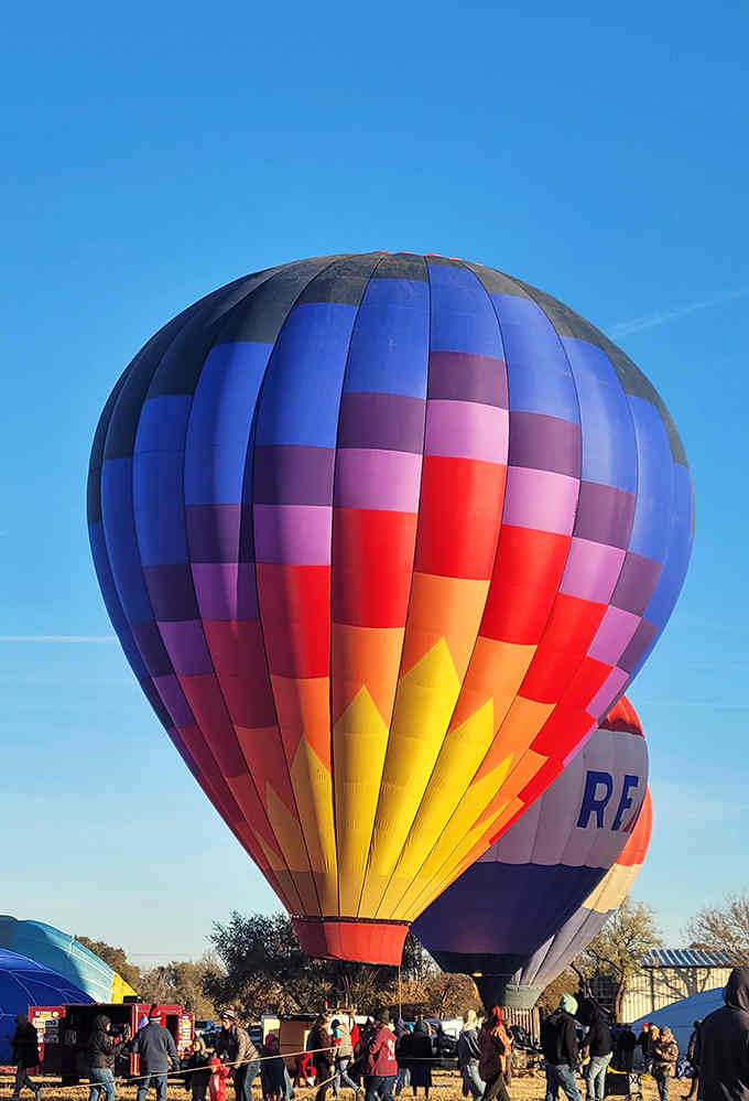 This hot air balloon's rainbow stripes against blue sky make you feel like a kid again, pure joy.