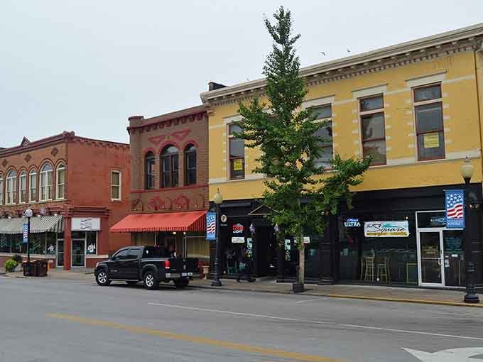 Cheerful awnings and American flags wave hello from storefronts where local businesses still thrive with pride.
