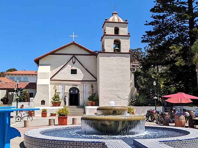 The historic mission's fountain sparkles under blue skies while bicycles wait patiently for their next coastal adventure ride.