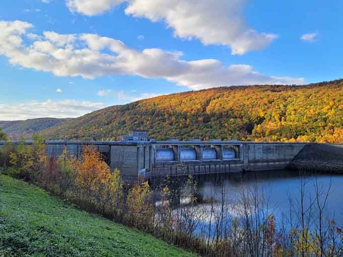 The dam stands solid against mountain backdrop while fall colors explode across ridges, reminding us why they call this God's country.