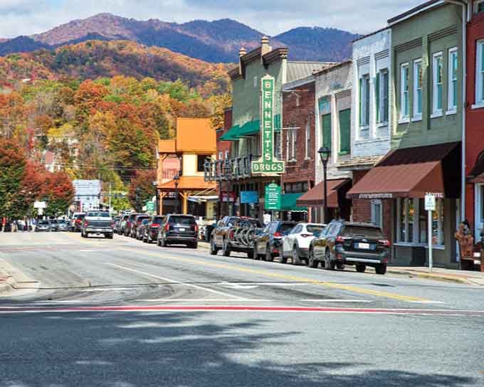 Autumn mountains frame colorful storefronts where the old-fashioned drugstore sign promises simpler times still exist.