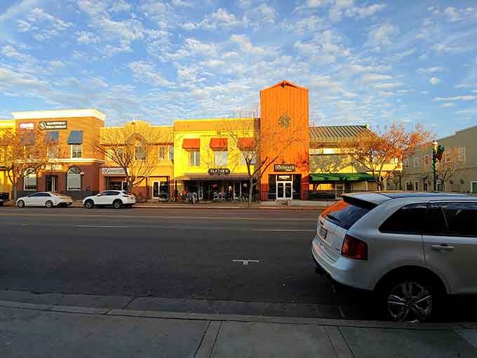 Sunset paints the storefronts in golden light while mountains stand guard in the distance watching over everything.