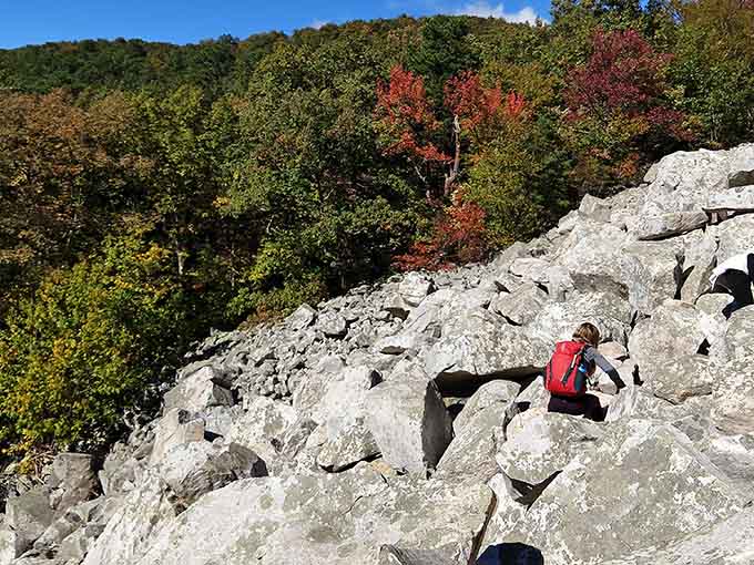 A hiker in red contemplates autumn's glory from atop these ancient rocks that look like nature's own abstract sculpture garden.