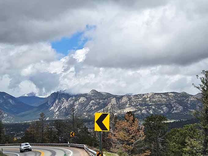 Storm clouds gather dramatically over the peaks as this winding byway promises adventure around every hairpin turn ahead.