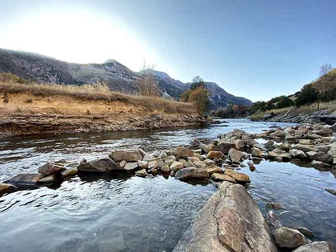 The gentle current flows past riverside rocks, creating the perfect setting for a peaceful mountain soak.