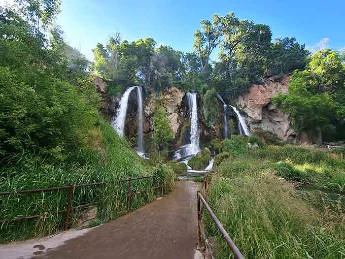 The wooden walkway leads visitors through lush greenery toward the triple falls, an easy path to extraordinary beauty.