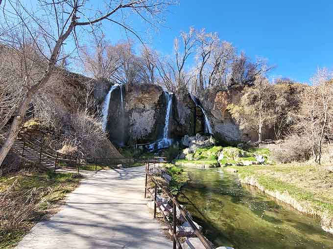 The paved walkway leads to cascading water and moss-covered rocks that feel more like Oregon than the Rockies.