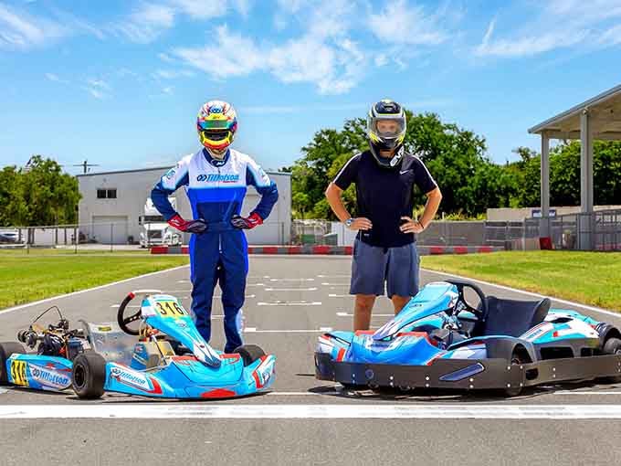 Two racers, helmets on and confidence high, standing trackside like it&rsquo;s race day&mdash;engines not needed.