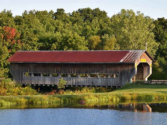 This weathered beauty with its rustic red roof proves that aging gracefully applies to bridges too.