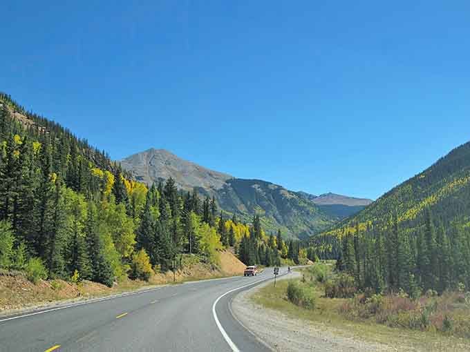 The open road beckons through aspens and evergreens, where every curve promises another postcard moment ahead.