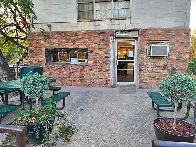 That weathered brick facade and those green picnic tables are your first clue that something special awaits inside.