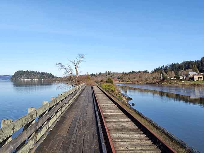 The old railroad tracks run parallel to your path, a reminder that trains once ruled this waterfront route.