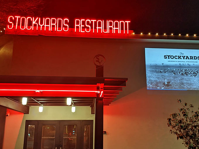 That glowing red neon sign beckons like a beacon for beef lovers everywhere, promising serious steakhouse satisfaction inside.