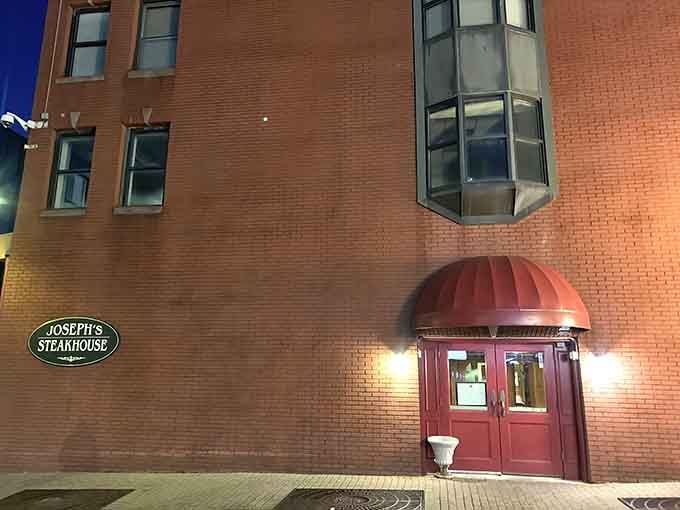 The welcoming glow of Joseph's at twilight, where that red awning promises dry-aged perfection and unforgettable meals await inside.