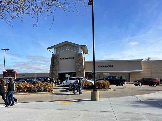 That stone-and-glass Coach storefront stands like a beacon of affordable luxury calling your name across the parking lot.