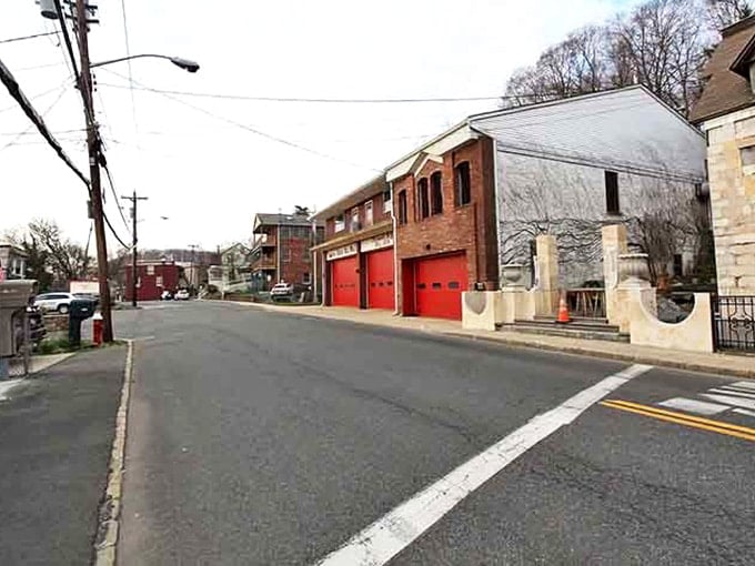 Quiet street in Piermont features brick buildings, bright red garage doors, and a welcoming small-town charm along a peaceful road.