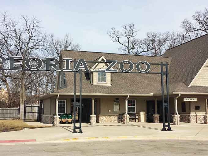 A welcoming entrance sign stands tall before a charming stone-accented building, inviting visitors to explore and discover amazing animals inside.