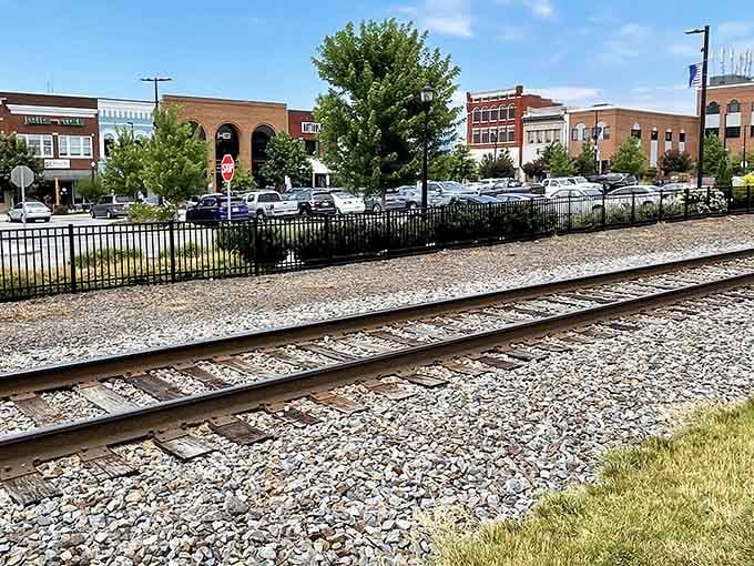 Explore this lovely downtown view across the gravel railroad tracks, where historic buildings and green trees sit under clear skies.