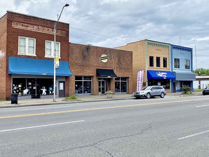 Those bright blue awnings pop against classic brick like a postcard from when downtowns actually thrived and mattered.