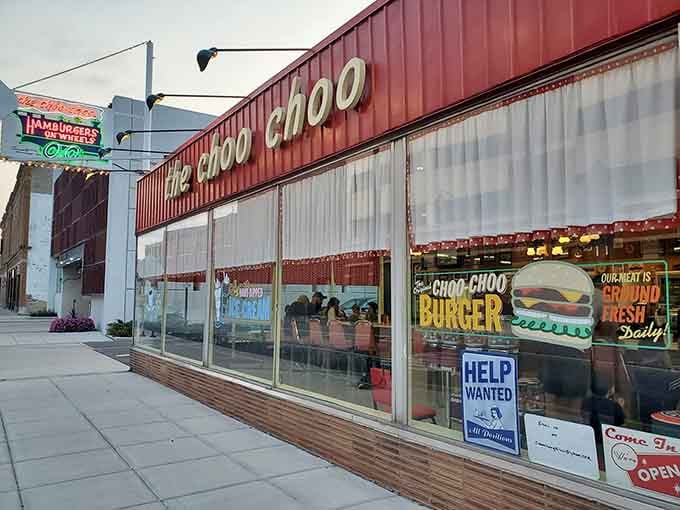 That vintage signage glowing against the twilight sky promises burgers delivered by train, because apparently regular waiters weren't whimsical enough.