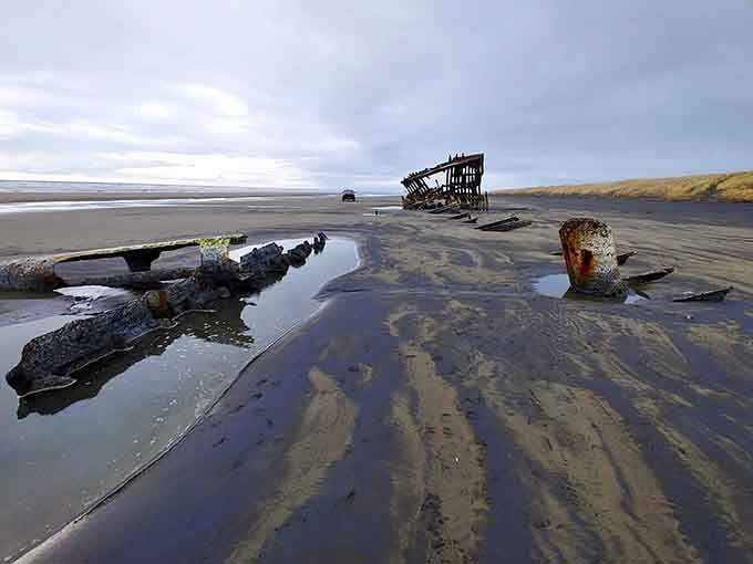 The Peter Iredale's skeletal remains create haunting reflections in tidal pools, nature's own mirror of maritime history.