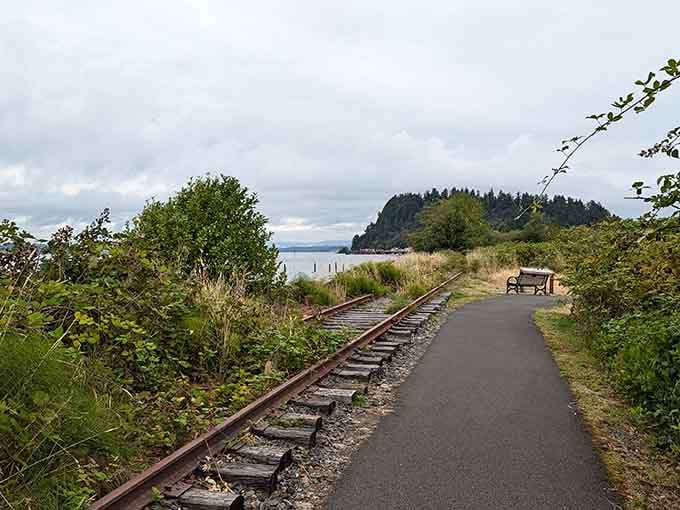 The old railroad tracks run parallel to your path, a reminder that trains once ruled this waterfront route.