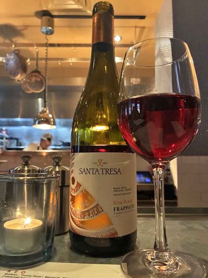 Italian wine paired with an open kitchen view, because watching culinary artistry enhances every sip you take.