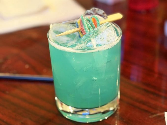 The Rainbow Dash cocktail glows turquoise and whimsical, garnished with candy that makes you smile before sipping.