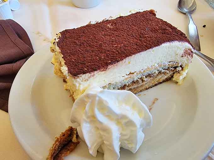 Tiramisu dusted with cocoa and served with a cloud of whipped cream, the perfect sweet ending to any meal.