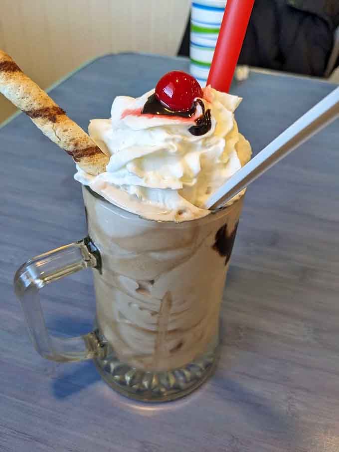 That vanilla milkshake topped with whipped cream and a cherry looks like it escaped from a 1950s soda fountain dream.