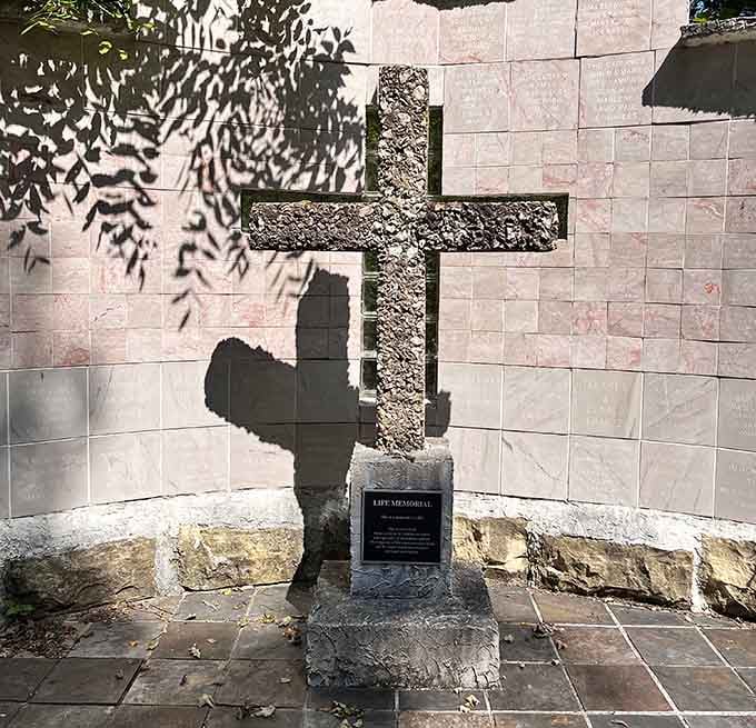 This stone cross memorial casts dramatic shadows, turning simple geometry into something profoundly moving.
