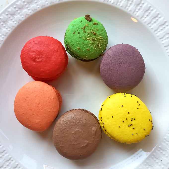 A rainbow of macarons arranged like edible jewels, each color hiding its own delicious secret filling inside.