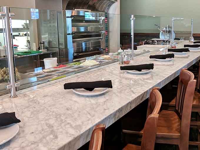 The marble counter with perfectly placed settings invites you to sit, watch, and prepare for culinary magic.