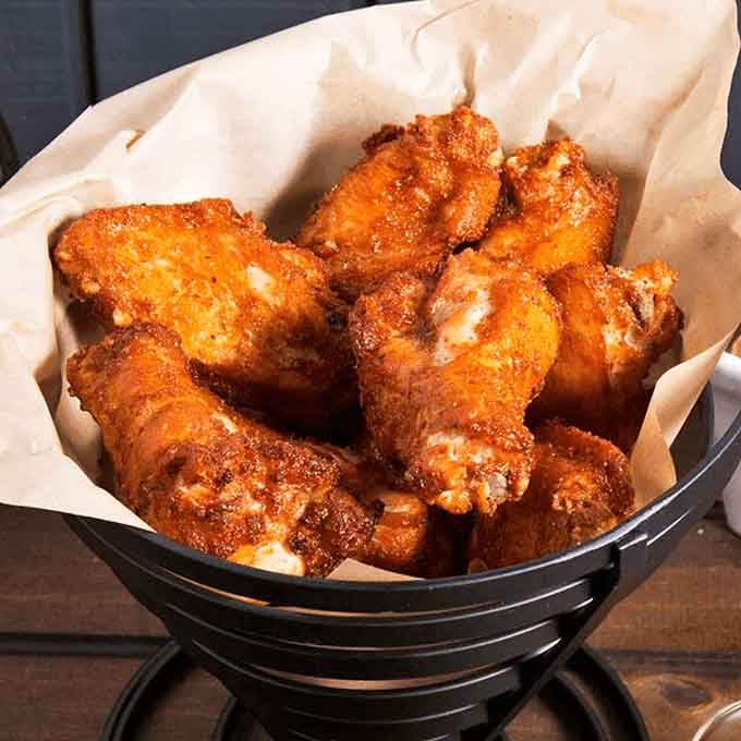 Crispy, saucy wings piled high in a basket are the perfect companion to any pizza order you're planning.