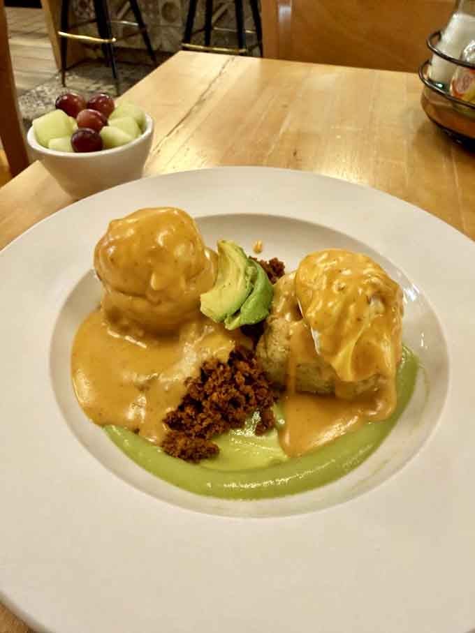 Poached eggs draped in golden hollandaise over chorizo and avocado salsa verde, pure morning magic on a plate.