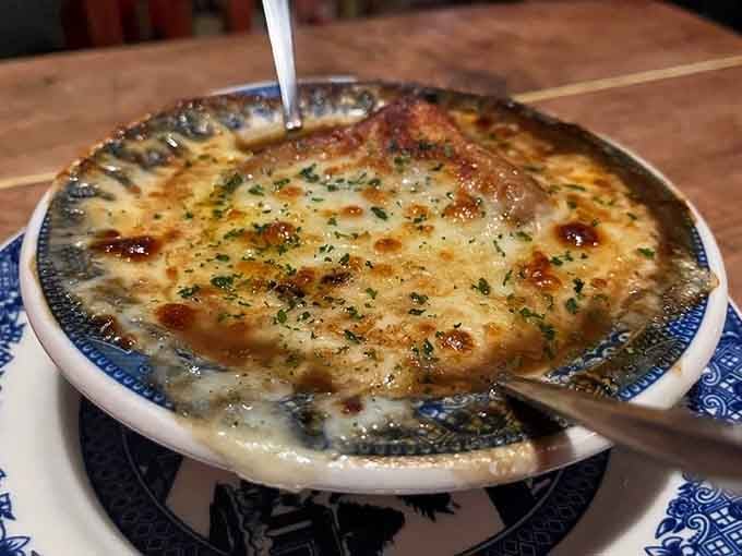 French onion soup with a cheese blanket so thick it practically requires architectural support to stay upright.