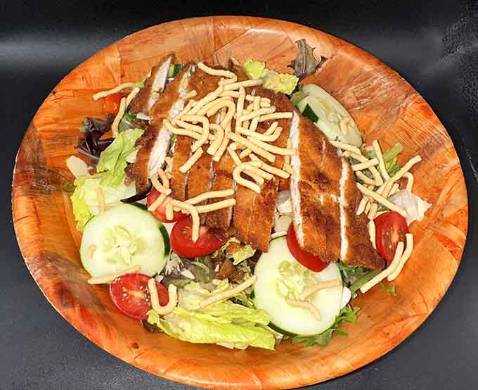 Crispy chicken atop fresh greens with shredded cheese shows that salads here aren't punishment; they're actually something you'd voluntarily order and enjoy.