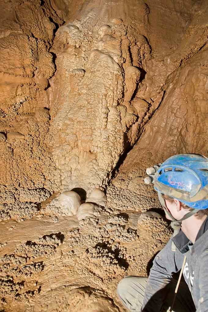 Flowstone formations cascade down the walls like frozen honey, created one mineral deposit at a time over millennia.