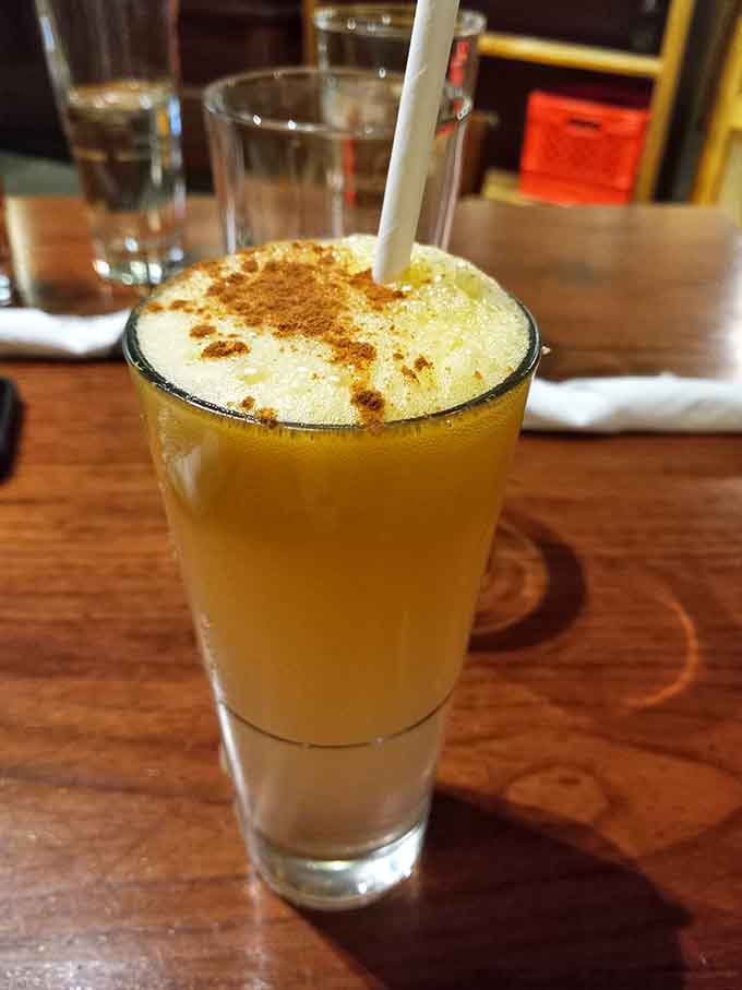 A golden cocktail topped with foam and spice, proving that breakfast beverages can be sophisticated and fun.