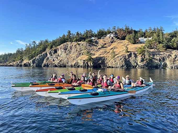 Kayakers glide past rocky shores, living their best REI catalog fantasy without the awkward studio lighting or fake smiles.