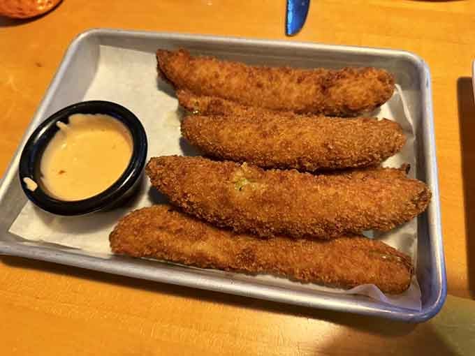 Golden fried pickle spears lined up perfectly, crunchy on the outside and tangy within, served with creamy dipping sauce.